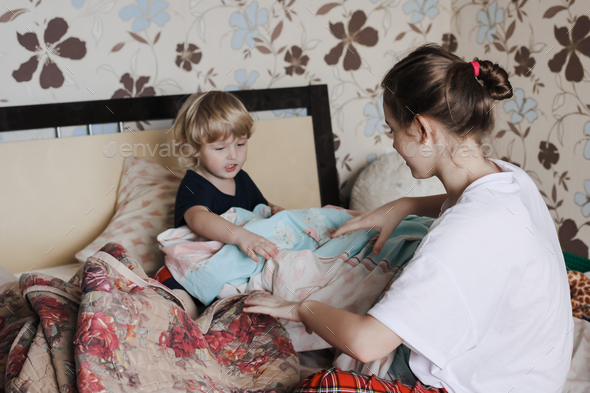 Children helping with cleaning the house, removing bed linen. Lifestyle ...