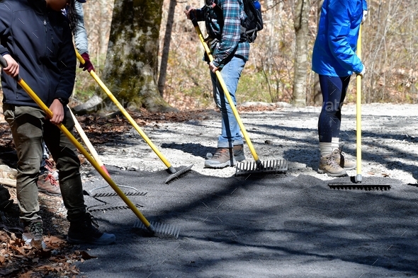 Doing community service by spreading gravel with rakes and shovels and ...