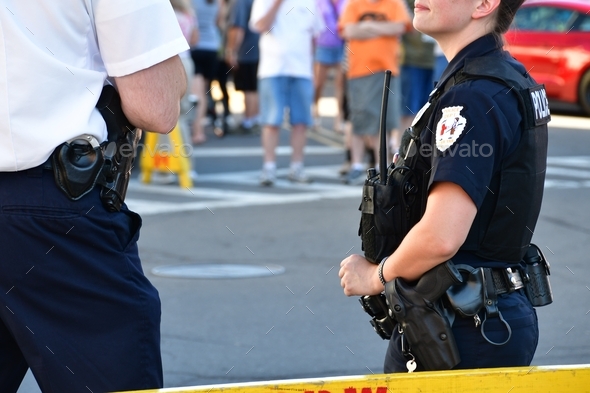 A male and female police officer standing guard behind a barricade ...