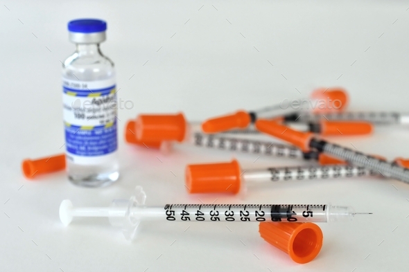 A vial of insulin medicine with a needle or syringe for injections ...