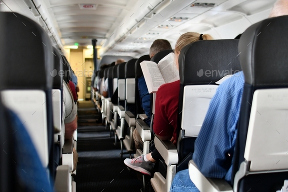 Passengers on an airplane enjoying a smooth flight while reading a book ...