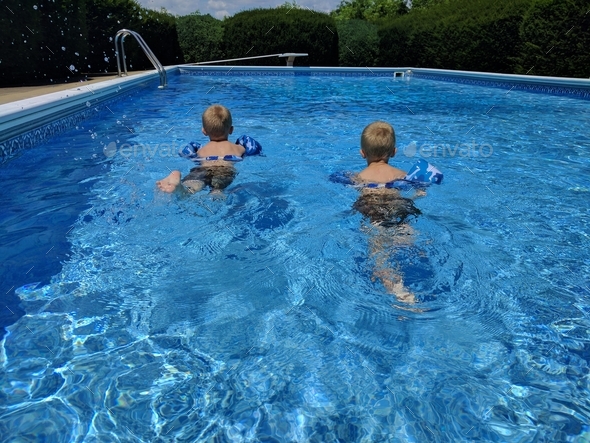 Boys Playing in the swimming pool with arm flotation devices splash ...