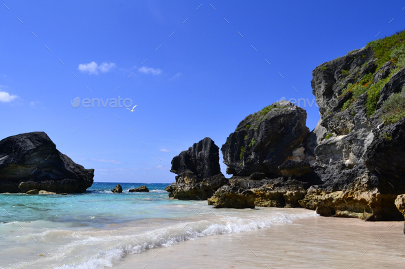 Rocks and pinks sand leading down to the clear blue waters off the ...