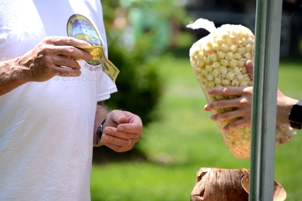 Purchasing a bag of popcorn at an outdoor carnival or fair with cash ...