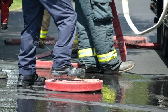 Firemen and fire hoses on wet pavement after fighting a fire ...