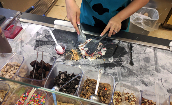 Mixing toppings into ice cream on a cold stone counter. Stock Photo by ...