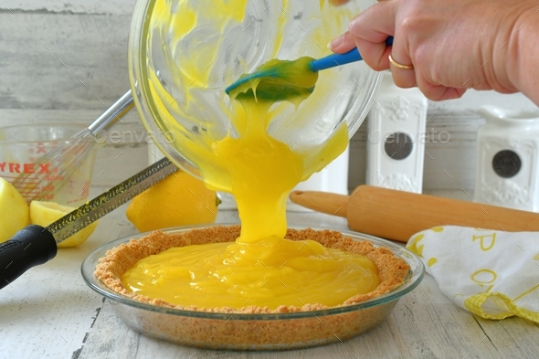 Pouring homemade lemon pie filling into graham cracker crust for a ...