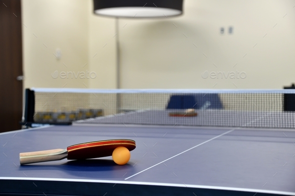 Ping pong paddle and ball on a ping pong table. Clean, modern game room ...