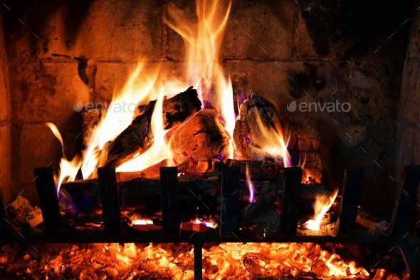A cozy wood fire burning in a fireplace to heat the room up and spread ...