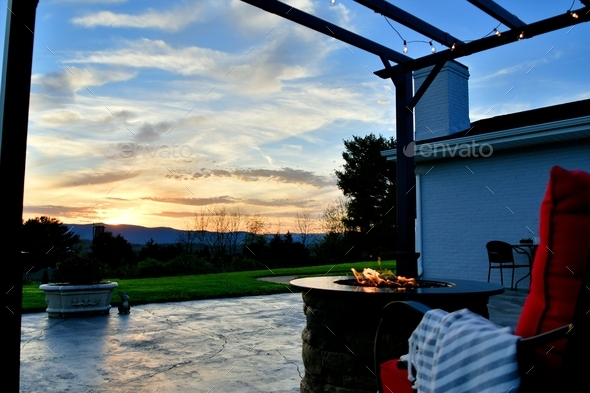Enjoying a sunset while relaxing around a fire in outdoor living space ...