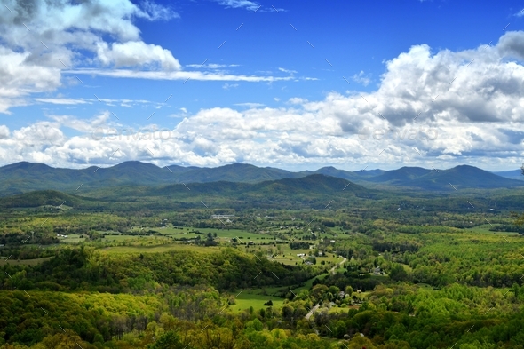 Looking over a valley to the mountains and a beautiful sky with puffy ...