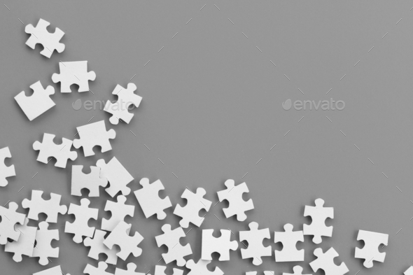 White jigsaw puzzle pieces scattered on gray background, copy space ...