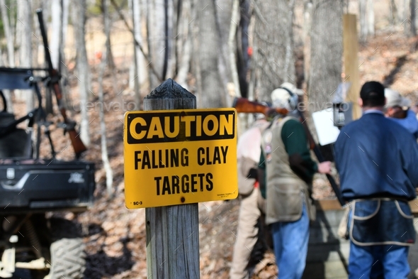 Caution, falling clay targets sign with men with shotguns in the ...