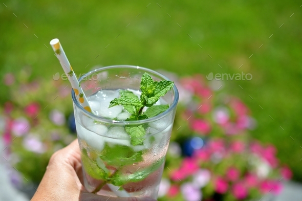 Cold refreshing glass of water with mint, ice cubes, & paper straw ...
