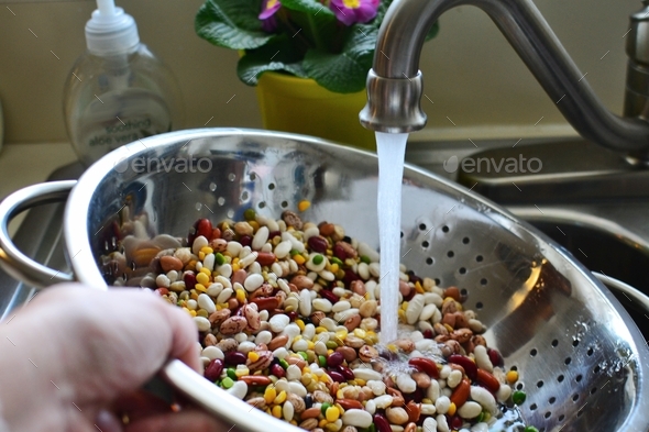 Rinsing dried beans in a colander or strainer under the running water ...