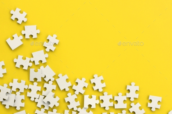 White jigsaw puzzle pieces scattered on yellow background, copy space ...