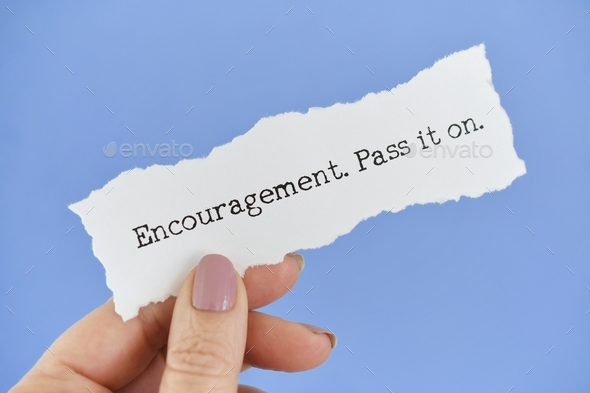 Encouragement. Pass it on. Female holding typewritten message ...