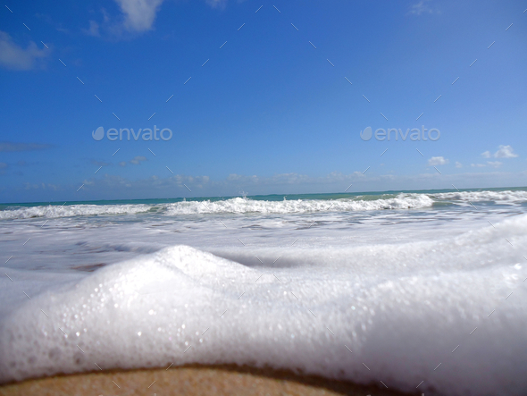 Sea foam on the beach up close at ground level. Sand, surf, ocean, low ...