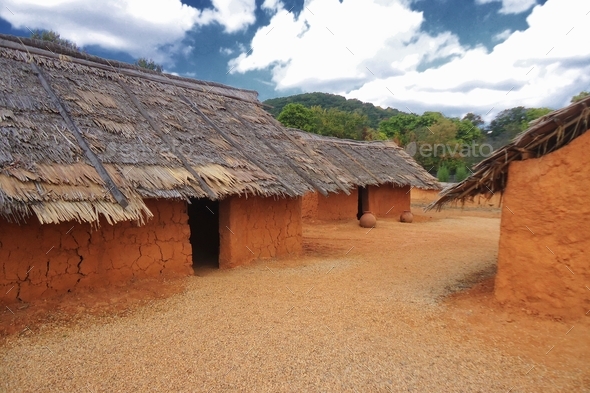 Orange clay huts with thatched roofs of west African village, exhibit ...