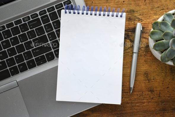 Blank unlined notebook & pen on laptop computer on desk workspace ...
