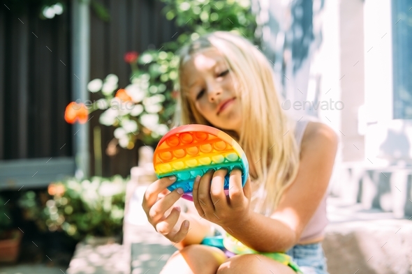 Girl playing with Poppit. New modern kid's antistress toy in the hands ...