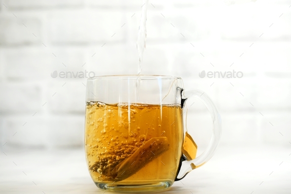 Making hot tea - pouring hot water over a teabag in a glass mug. Stock ...