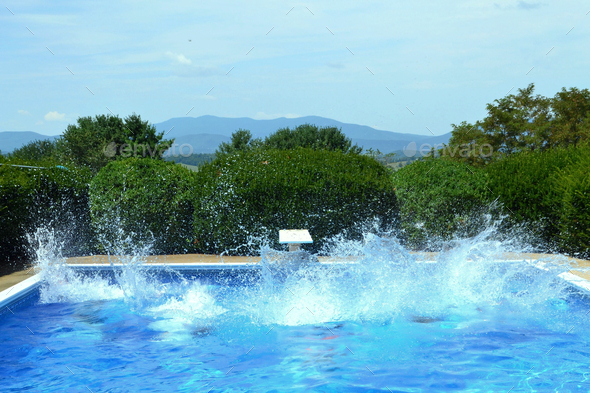 Several people jumping into a swimming pool and making a big splash ...