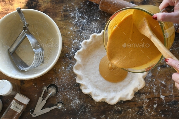 Making pumpkin pie pouring filling into crust pastry overhead high ...
