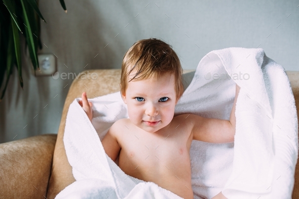 Cute child with blue eyes wrapped in a white towel. Clean baby after ...