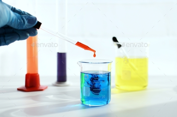 Mixing different colored chemicals in science beakers for chemistry lab ...