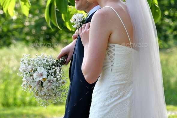 Bride with a bouquet of flowers standing next to the groom outside her ...