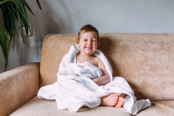 Cute child with blue eyes wrapped in a white towel. Clean baby after ...