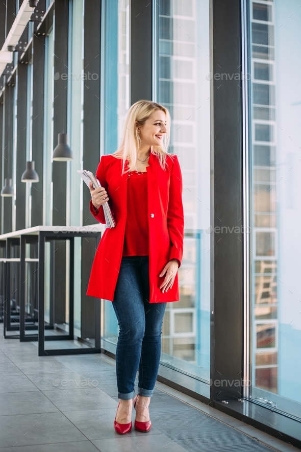 Attractive successful business lady in a red suit in a light office ...