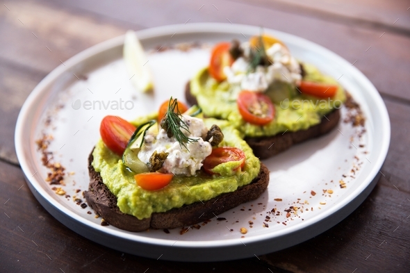 Smashed avocado with tomatos and feta cheese on toasts. Healthy food ...