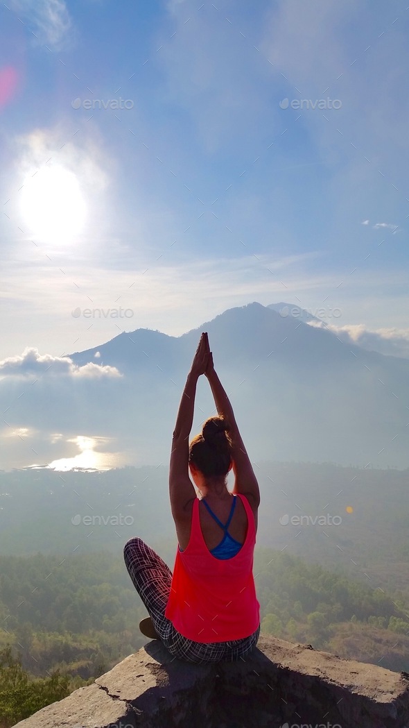 Young millennial woman practicing yoga meditation at the top of the ...