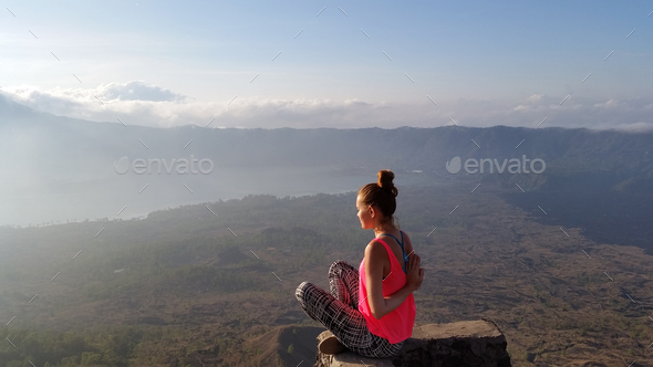 Backward namaste yoga pose at the top of the volcano Batur. Young woman ...
