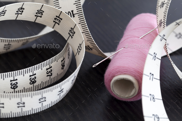Measuring tape and sewing needle in a spool of thread Stock Photo by ...
