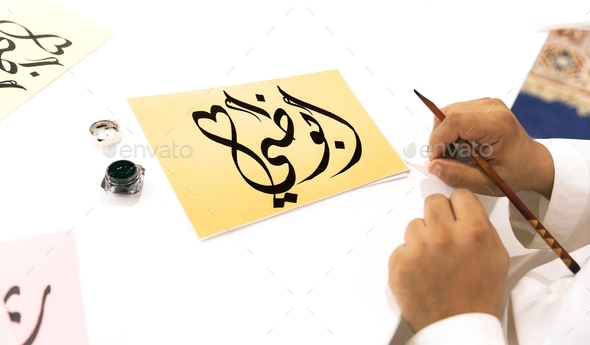 Word ‘Abu Dhabi’ written using Arabic calligraphy, hands of an artist ...