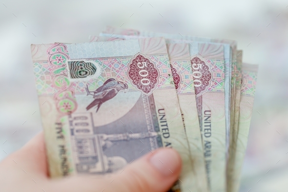 Stack of UAE dirhams in woman's hands. Closeup. Banknotes of five ...