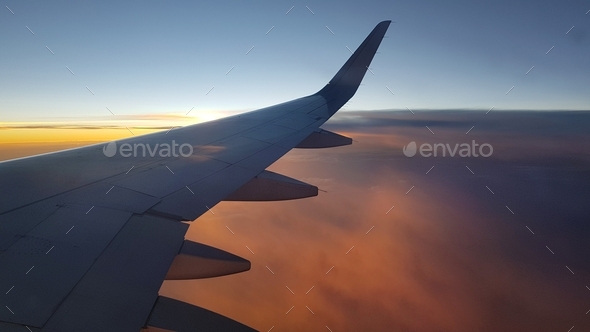 Plane flying up high in the sky at the sunset, showing horizon, wing of ...