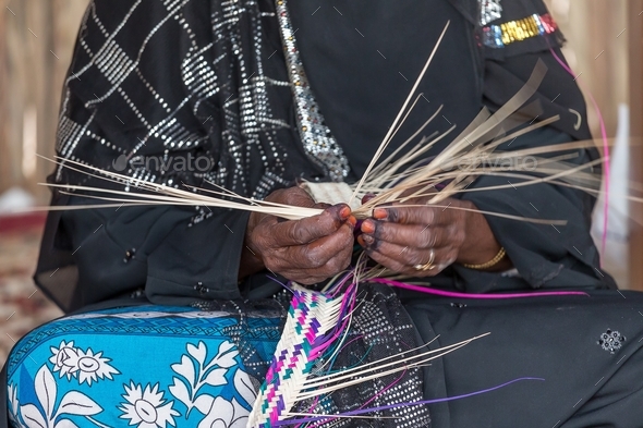 Emirati woman is weaving traditional basket from palm leaves, slow ...