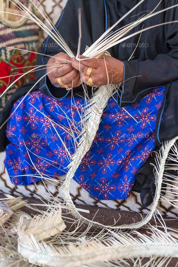 Emirati woman is weaving traditional basket from palm leaves, slow ...