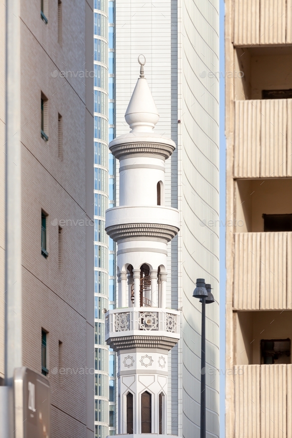 Minaret of the mosque in Abu Dhabi surrounded by modern high rise ...