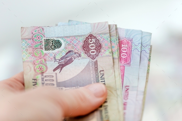 Stack of UAE dirhams in woman's hands. Closeup. Banknotes of five ...
