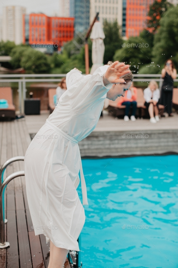 A young beautifully dressed woman in a white dress jumped in the pool ...