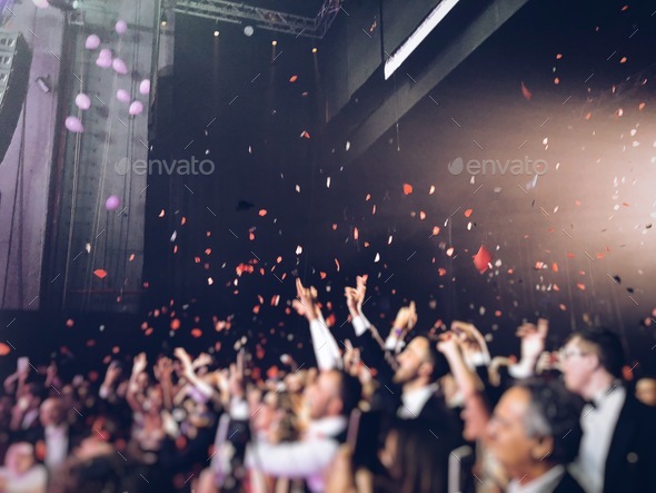 A crowd of people celebrating and dancing and having fun with confetti ...