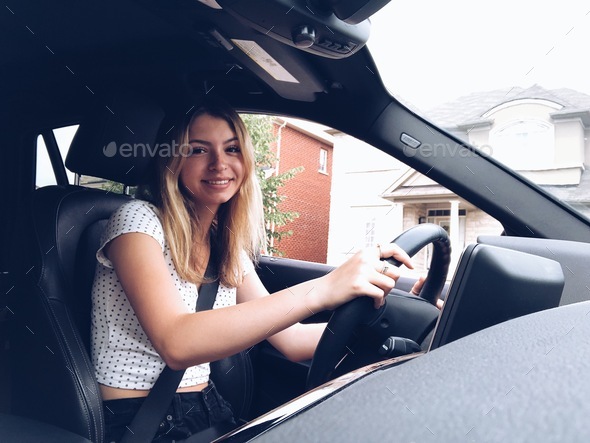 Happy young teenage girl smiling while taking her first driving lessons ...