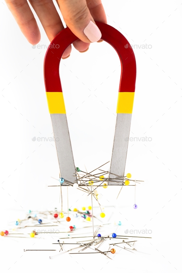 Woman’s hand is holding a colorful magnet and pins and needles attached ...