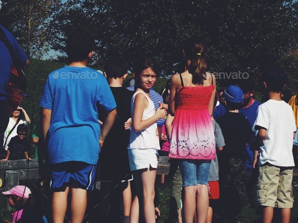Young girl is standing in the crowd of kids and looking back while ...