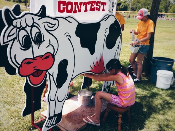 Children pretending learning how to milk a fake cow at a summer ...